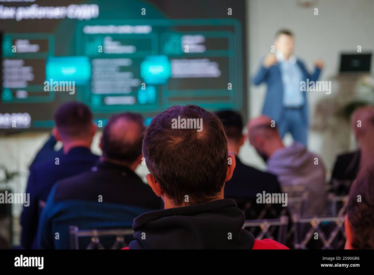Audience engaged in business presentation, blurred focus on speaker ...