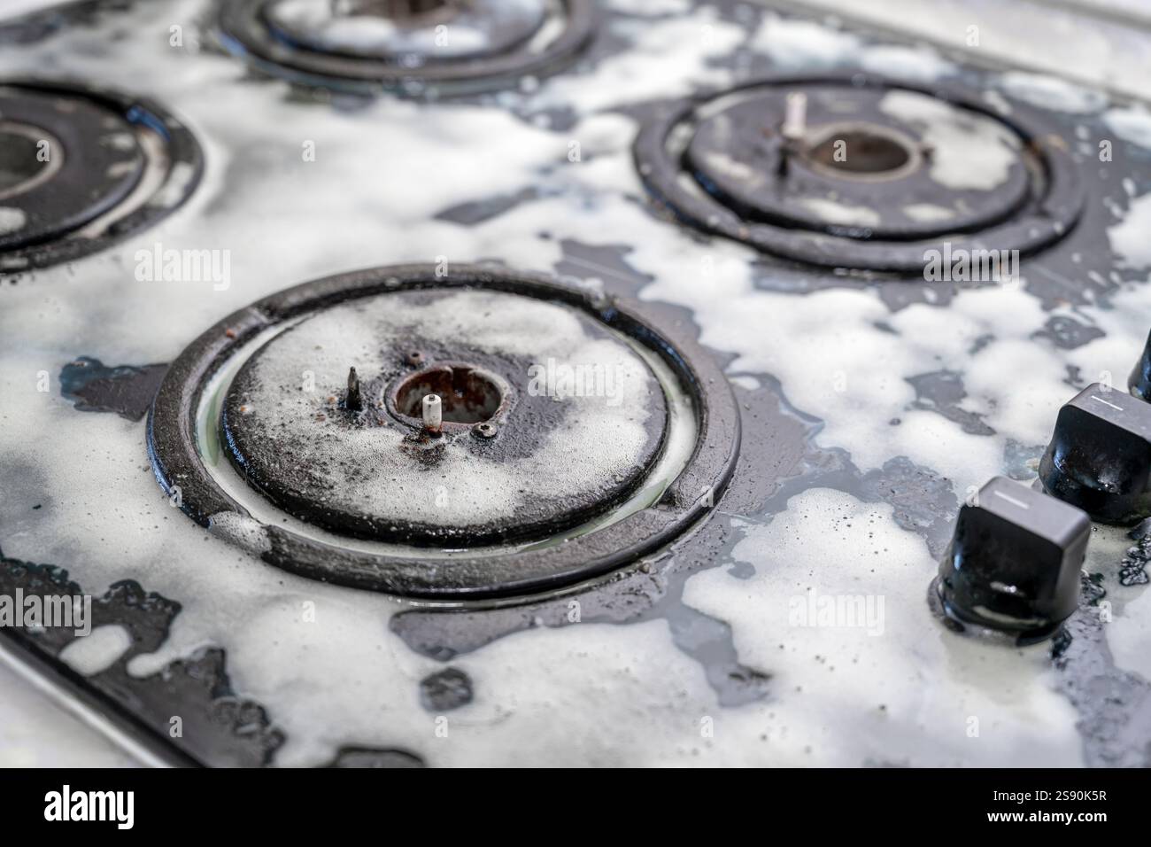 Cleaning a gas stove with kitchen utensils, household concepts, or ...