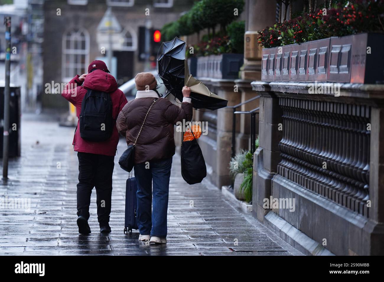 A couple battle with an umbrella in the wind during Storm Eowyn on ...
