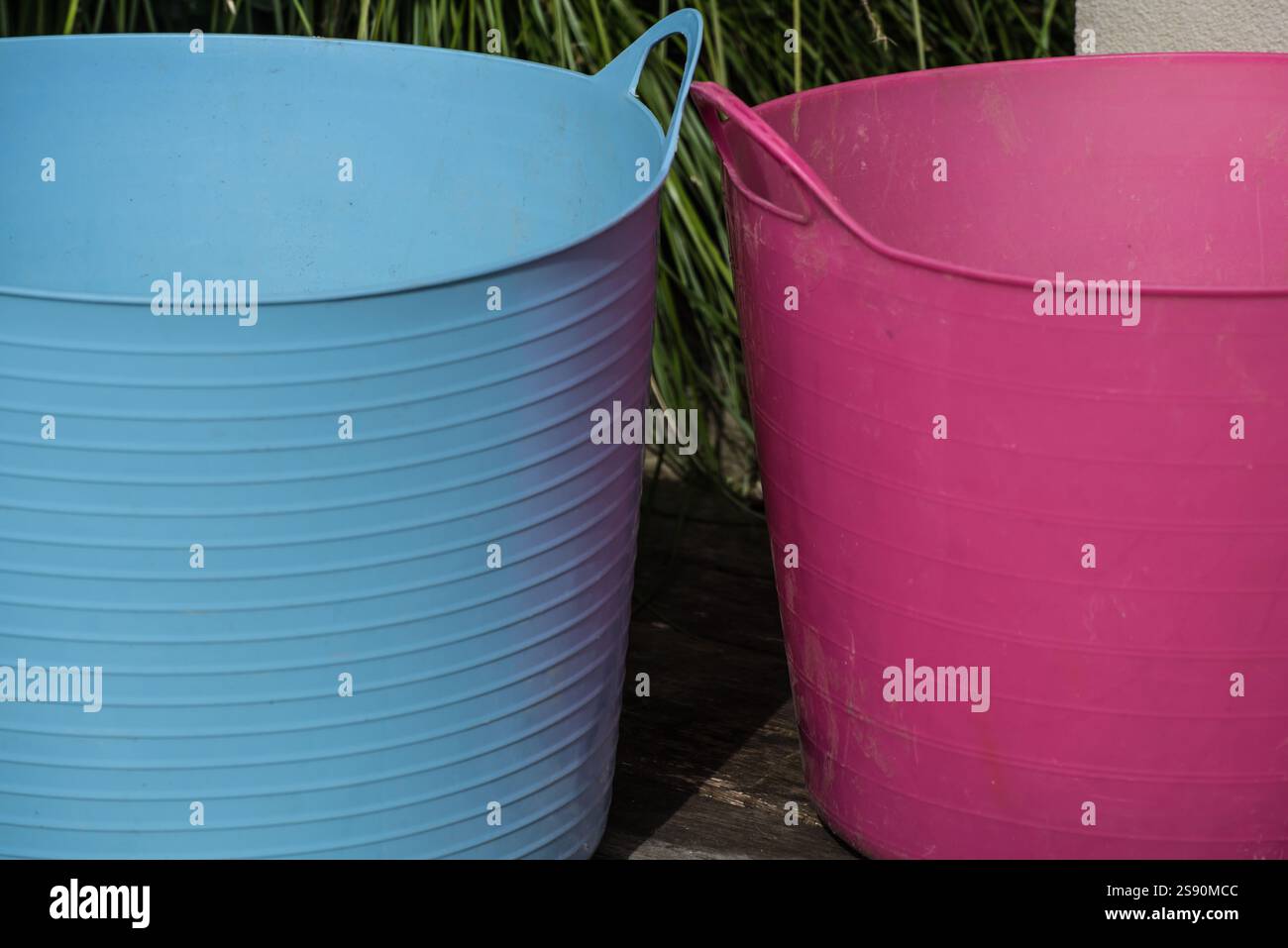 A bright blue and a bright pink plastic tub sitting side by side in a ...