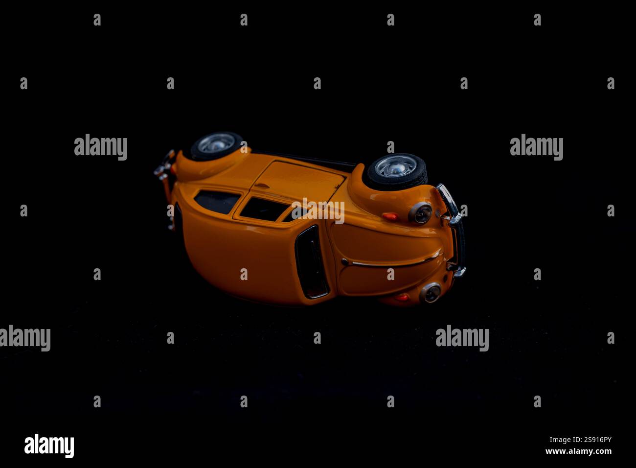 Yellow toy Volkswagen classic Beetle car overturned on a black ...