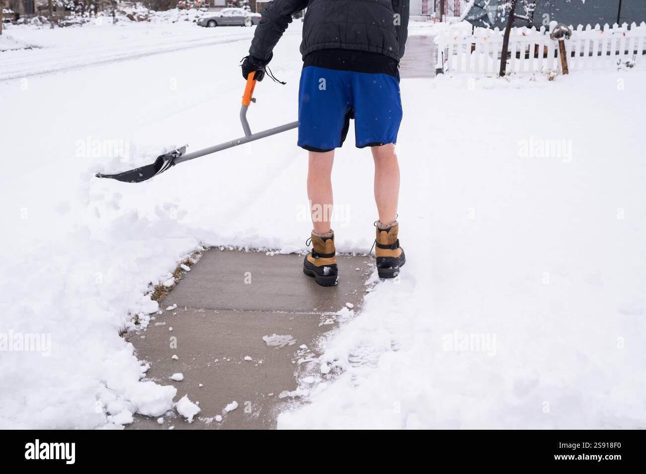 Man shoveling snow from sidewalk in gym shorts Stock Photo - Alamy