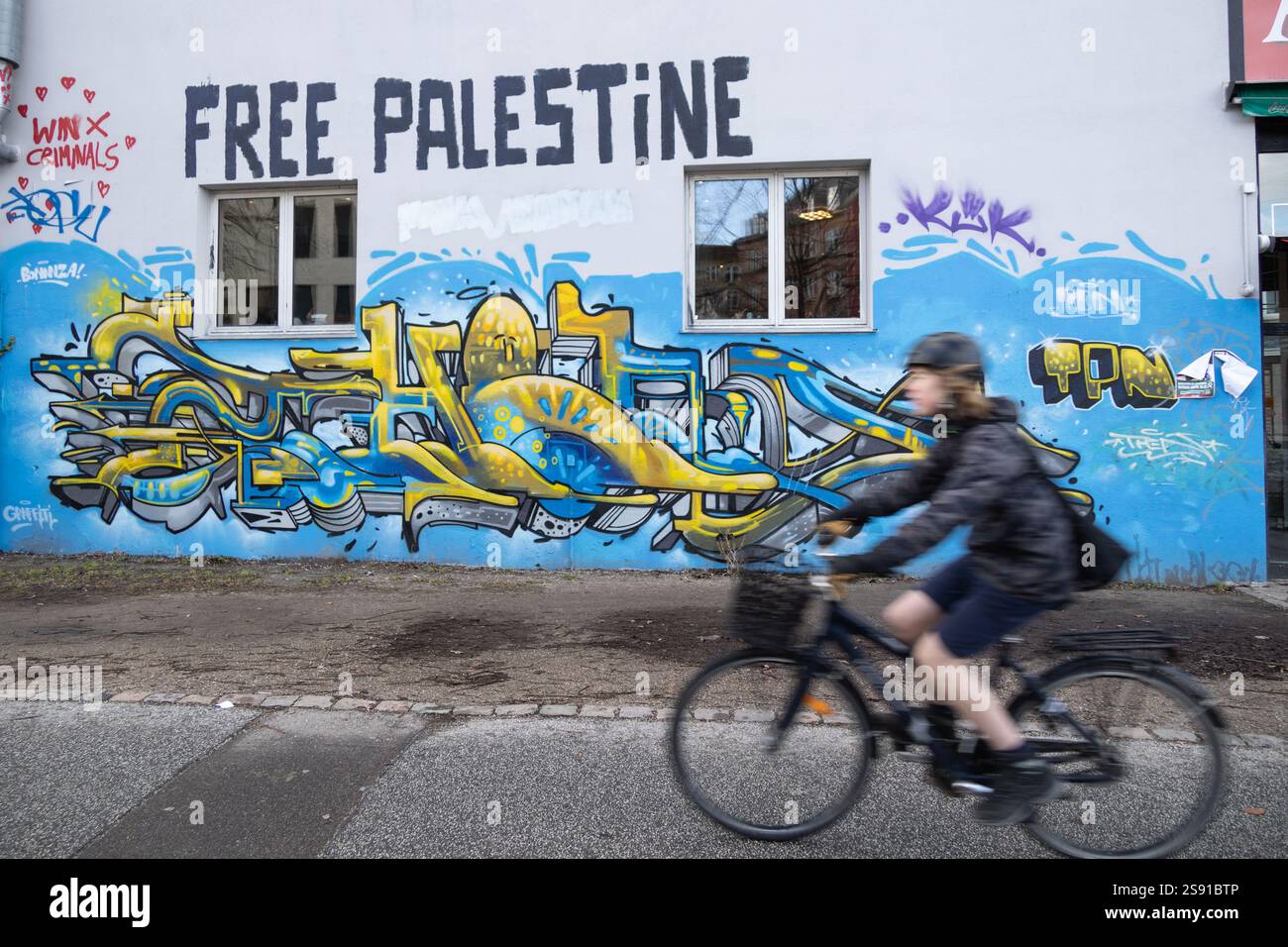 A cyclist rides past a wall with graffiti that says "Free Palestine" at ...