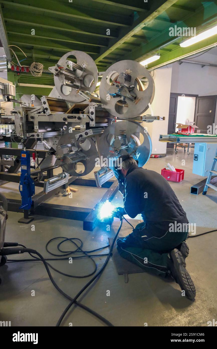 A person wearing a welding mask works on metal with a welding torch ...