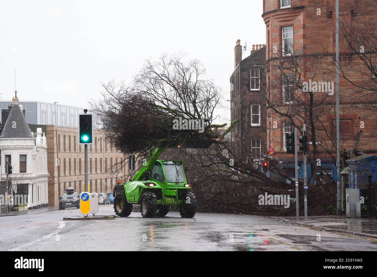 Workers remove a fallen tree on Regent Road, Edinburgh. Schools have ...