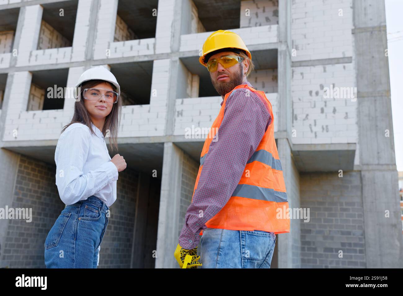 Construction workers reviewing blueprints on site, showcasing teamwork and expertise in ...