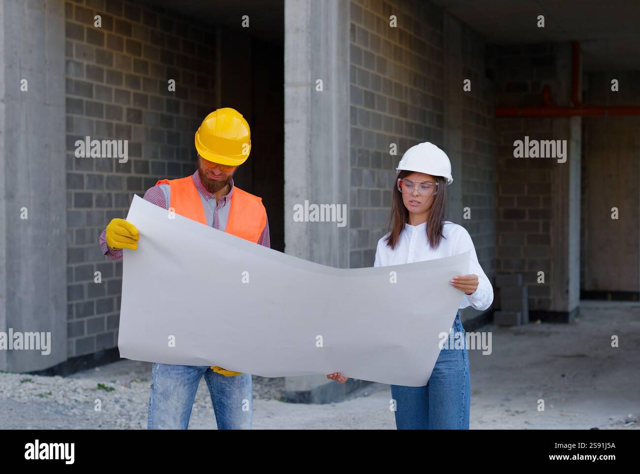 Construction workers are carefully reviewing a blueprint on a building ...