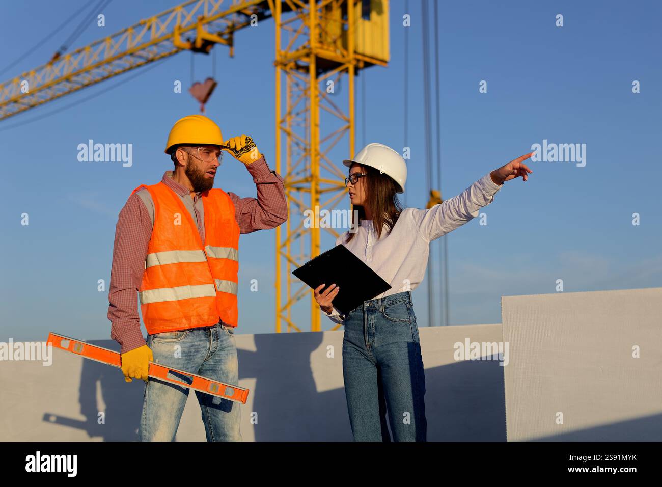 Female engineer holding clipboard and pointing while discussing ...
