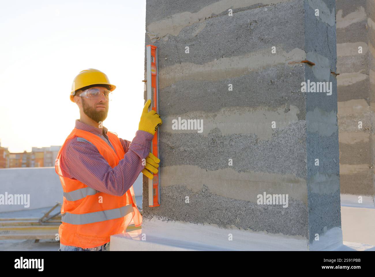 Construction worker checks wall verticality at sunset with a spirit ...