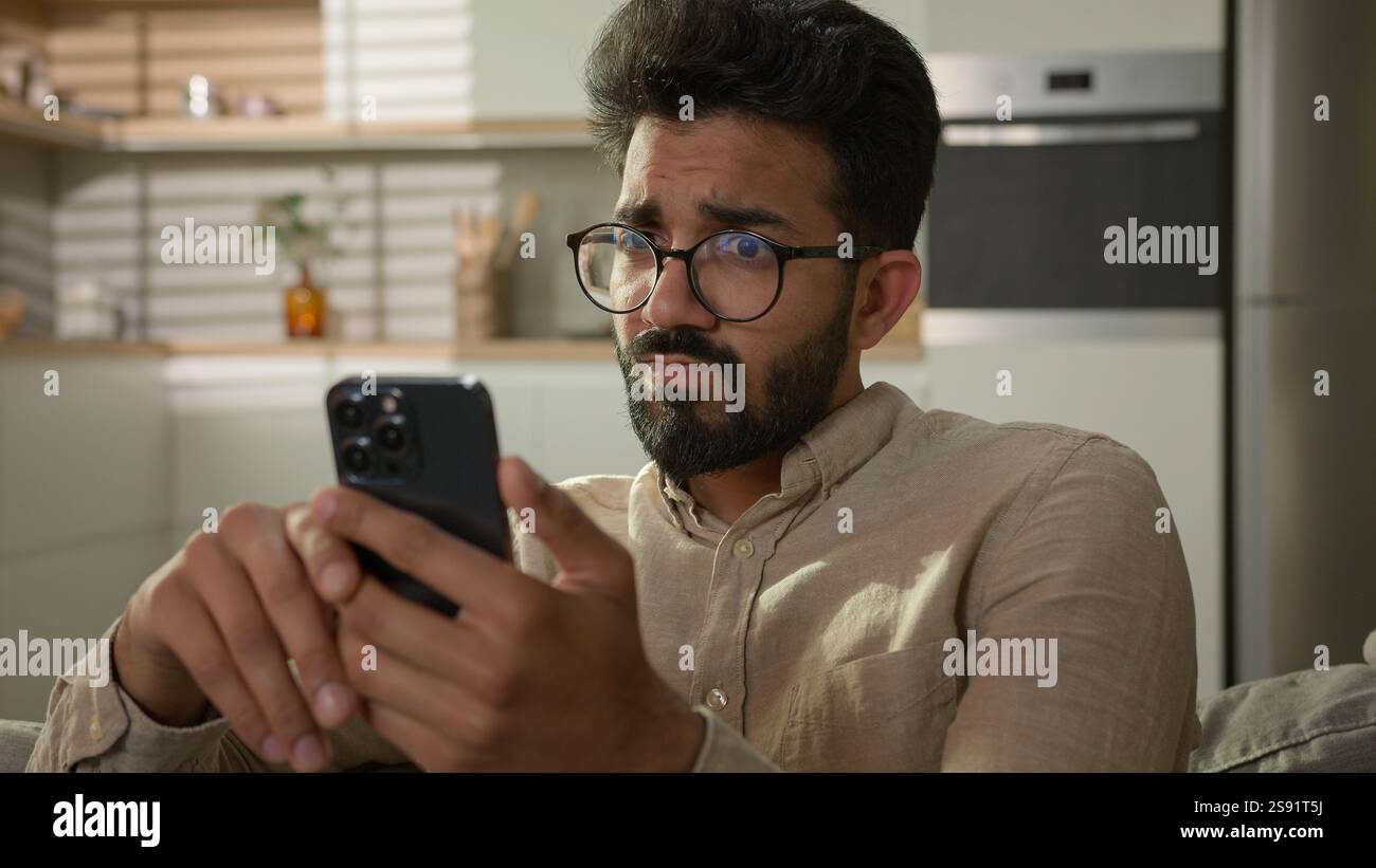 Arabian Indian ethnic man guy use mobile phone on couch browsing mobile ...