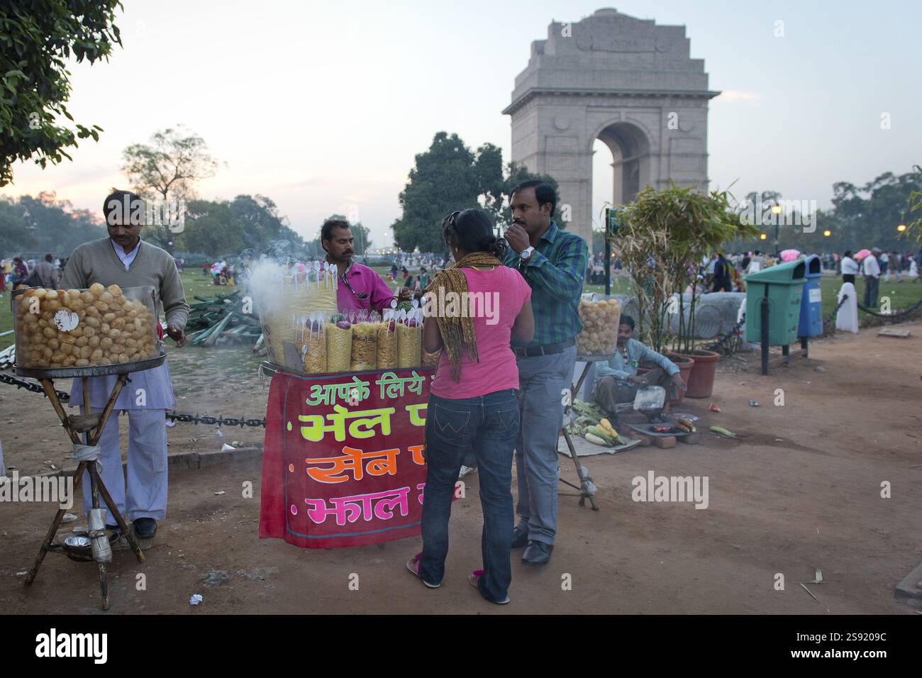 Men standing at a food stall selling snacks in front of the Amar Jawan ...
