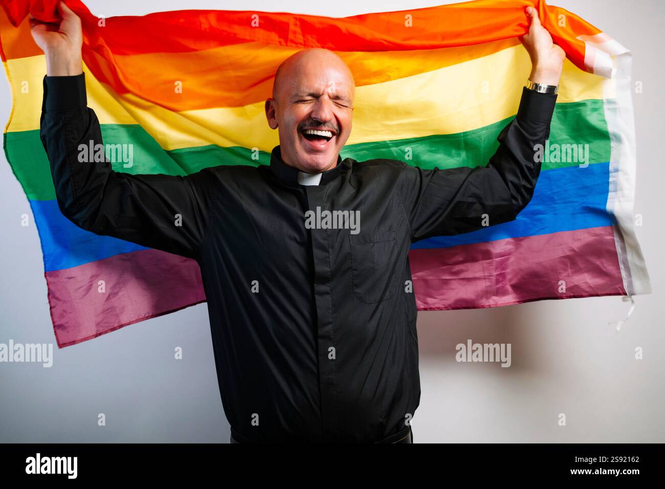 Portrait of a priest with a multi-colored LGBT flag Stock Photo - Alamy