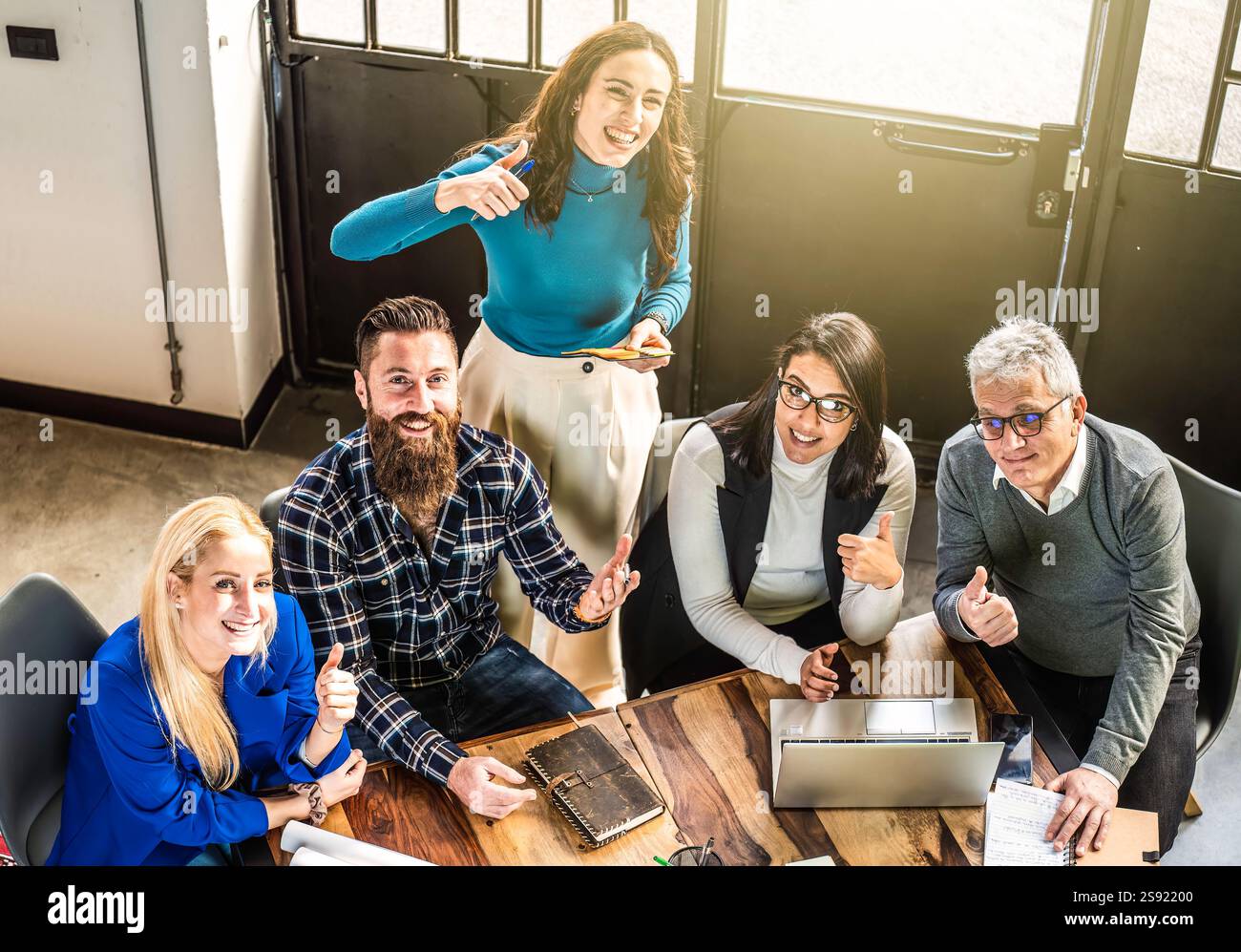 Team of diverse professionals giving thumbs-up around a meeting table ...