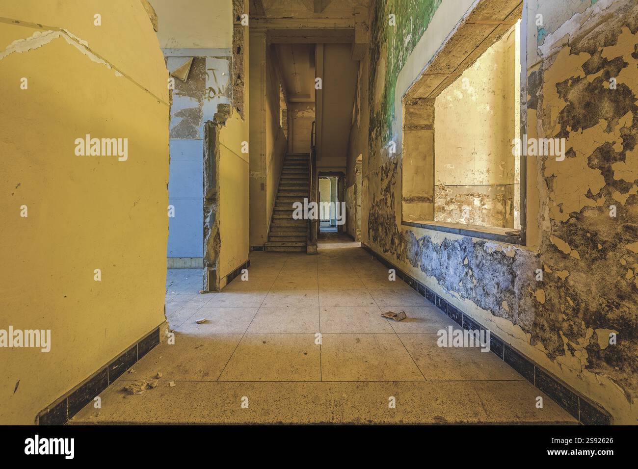 Stylishly dilapidated hallway with straight stairs and peeling walls ...