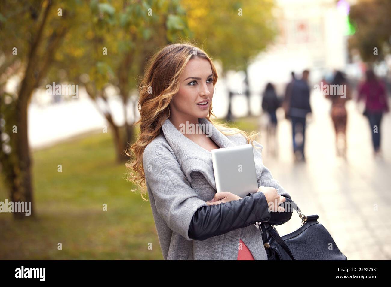 A businesswoman with a tablet walking in a city park Stock Photo - Alamy