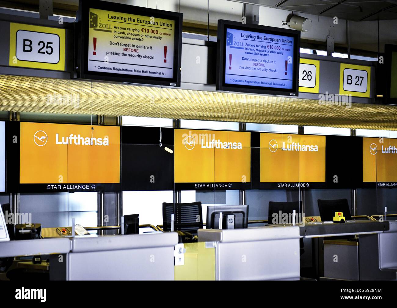 Empty Lufthansa counters at an airport with yellow display panels, a ...