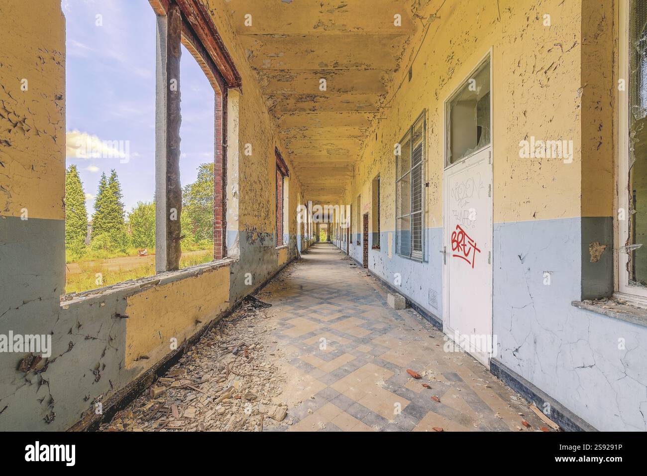Long, dilapidated corridor in abandoned building with graffiti and ...