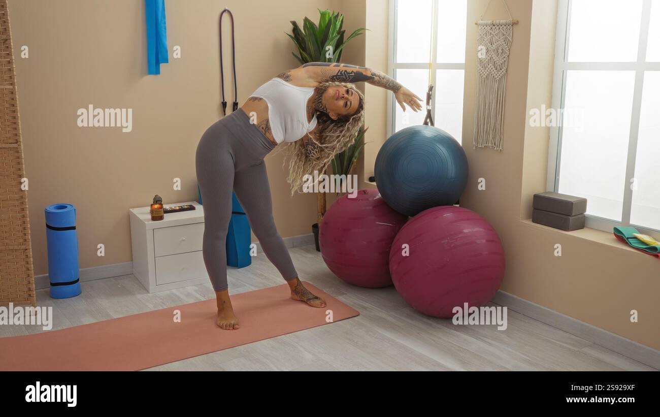 Woman stretching indoors at a gym with exercise balls and yoga ...