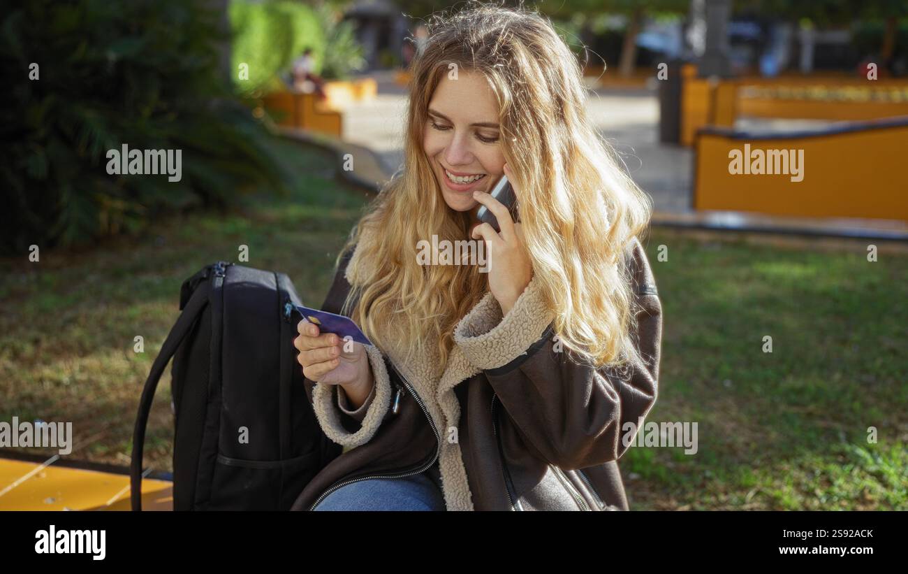 Woman smiling while holding smartphone in outdoor park setting ...