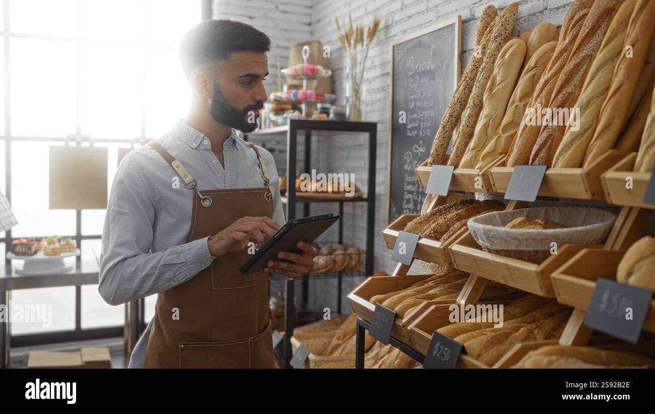 Young hispanic man with a beard stands in a bakery shop using a tablet ...