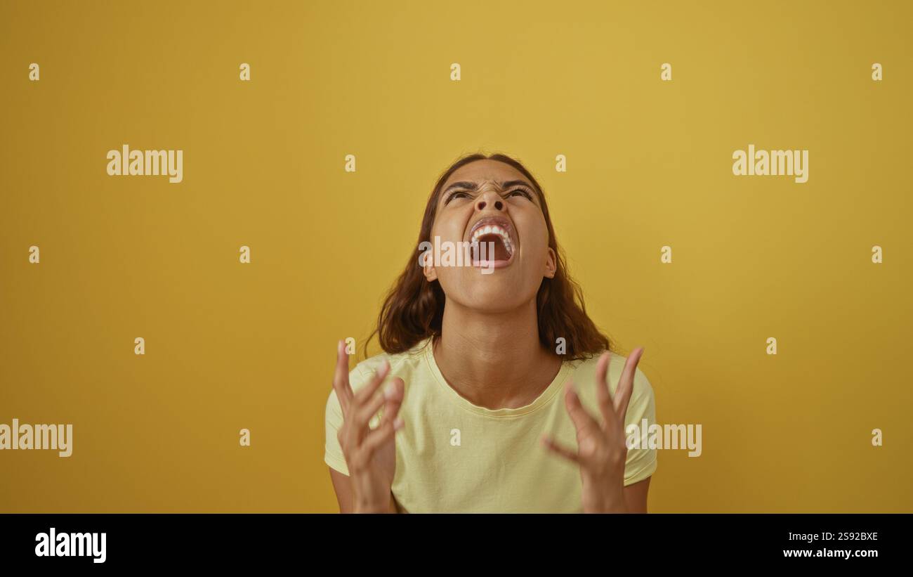 Woman screaming in frustration with open mouth and hands raised against ...