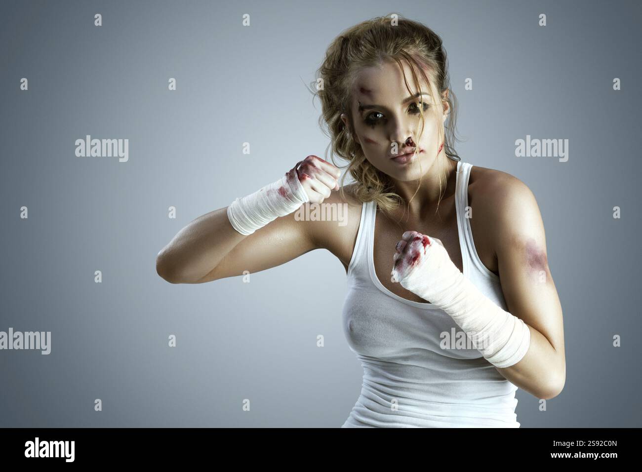 Aggressive female fighter with bruises, wearing a bloody bandage around ...