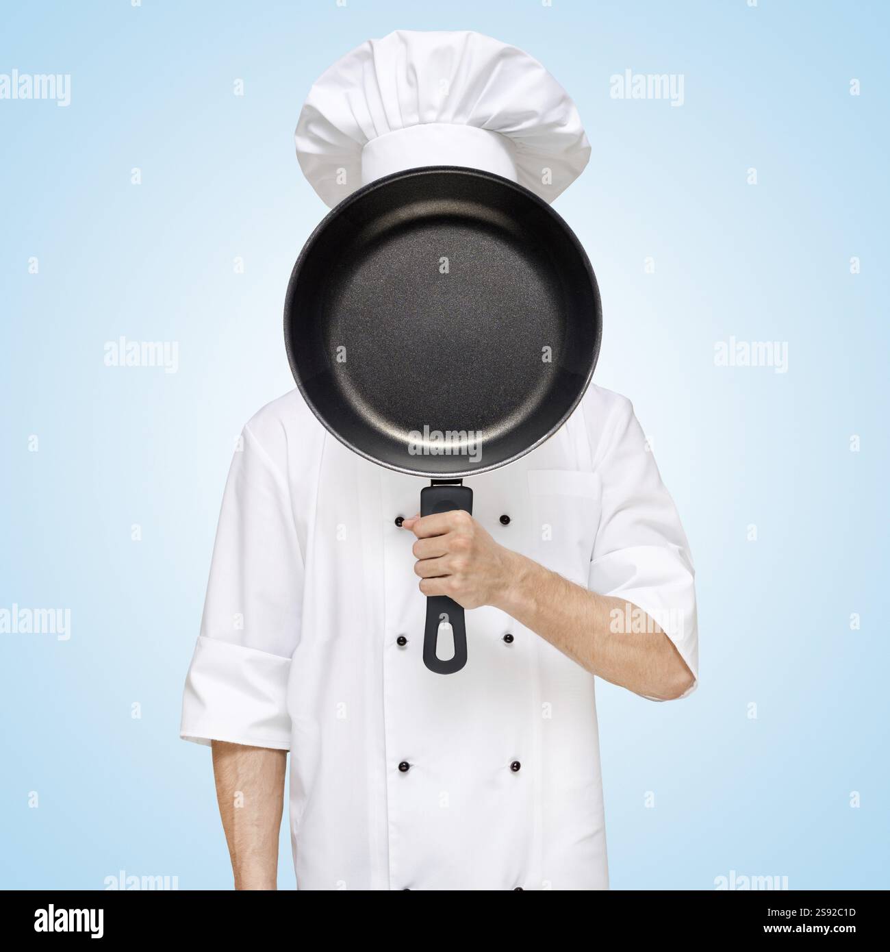 Restaurant chef hides behind a frying pan for a business lunch menu ...