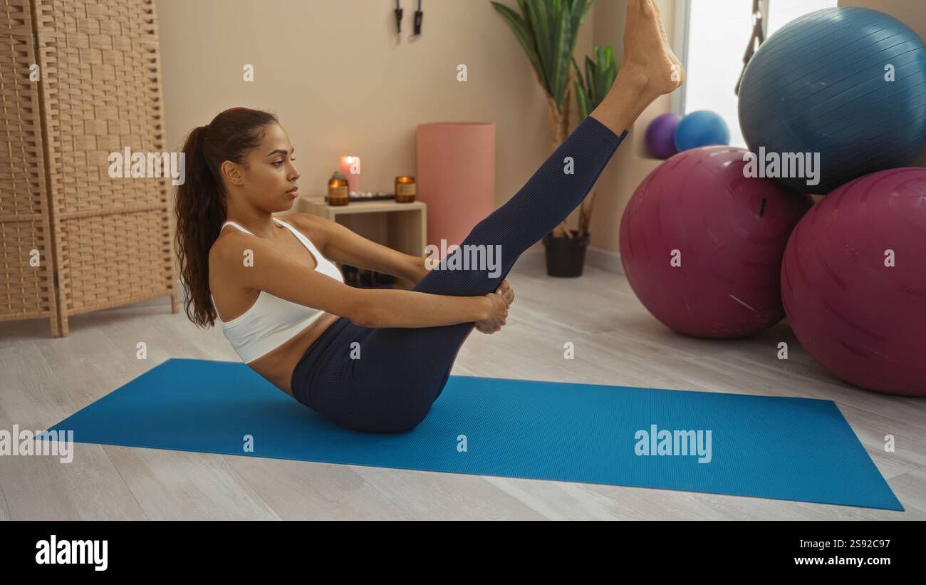 Woman practicing yoga on a mat in an indoor gymnasium surrounded by ...