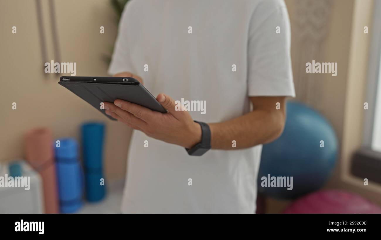 Man holding tablet in gym setting with exercise equipment indicating ...