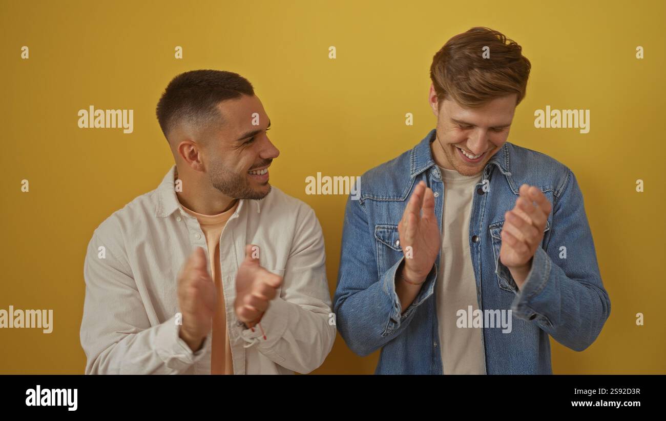 Handsome men clapping together in friendship against a yellow wall ...