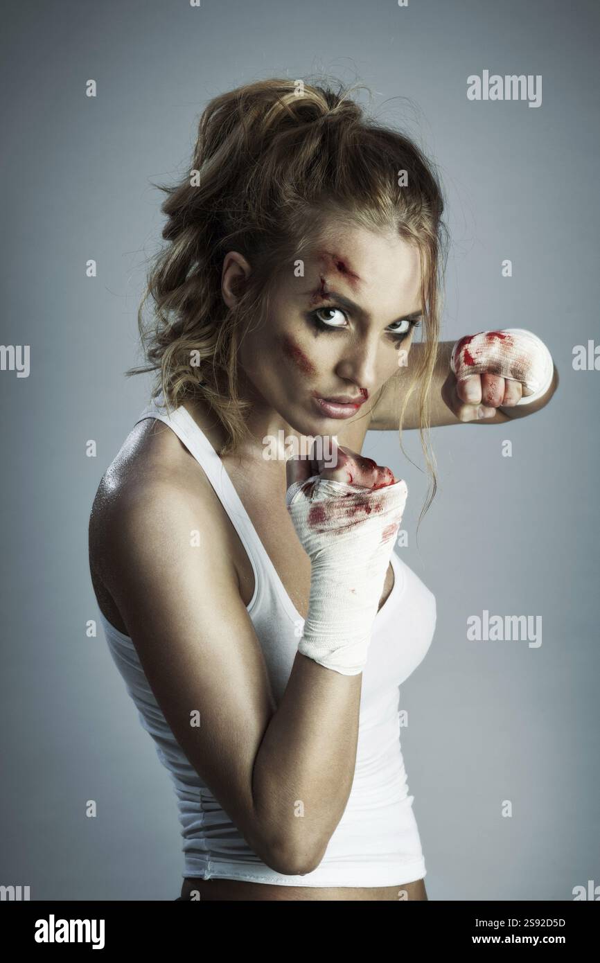 Aggressive female fighter with bruises, wearing a bloody bandage around ...