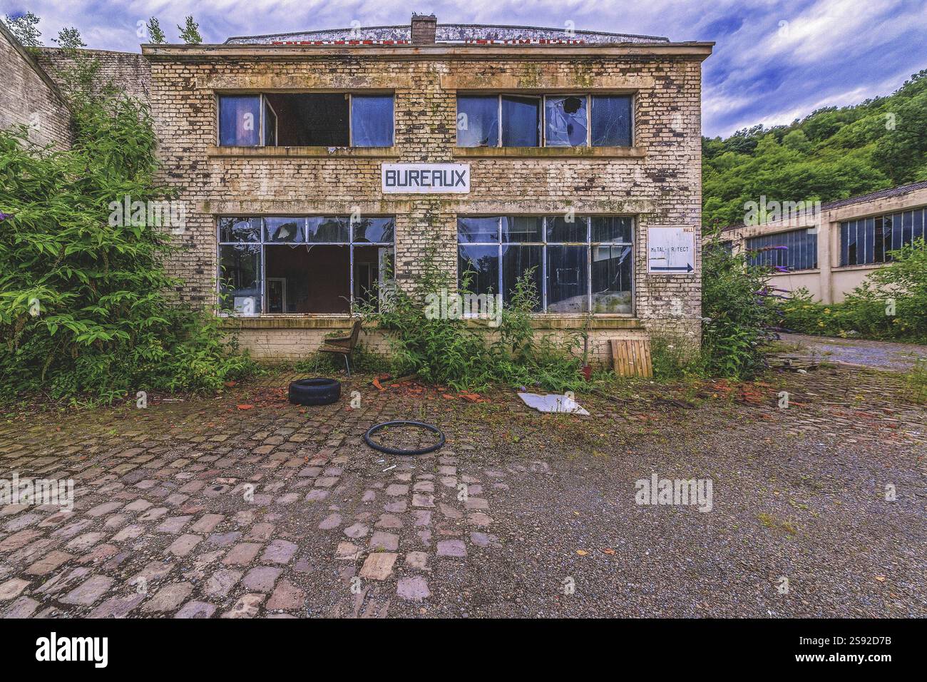 An old, abandoned office building with a crumbling facade and overgrown ...