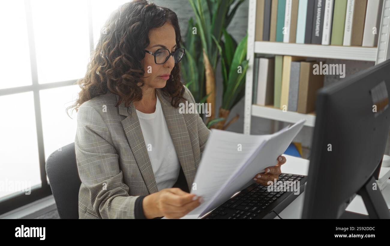 Woman reading documents in modern office, showcasing focus and concentration, wearing glasses ...
