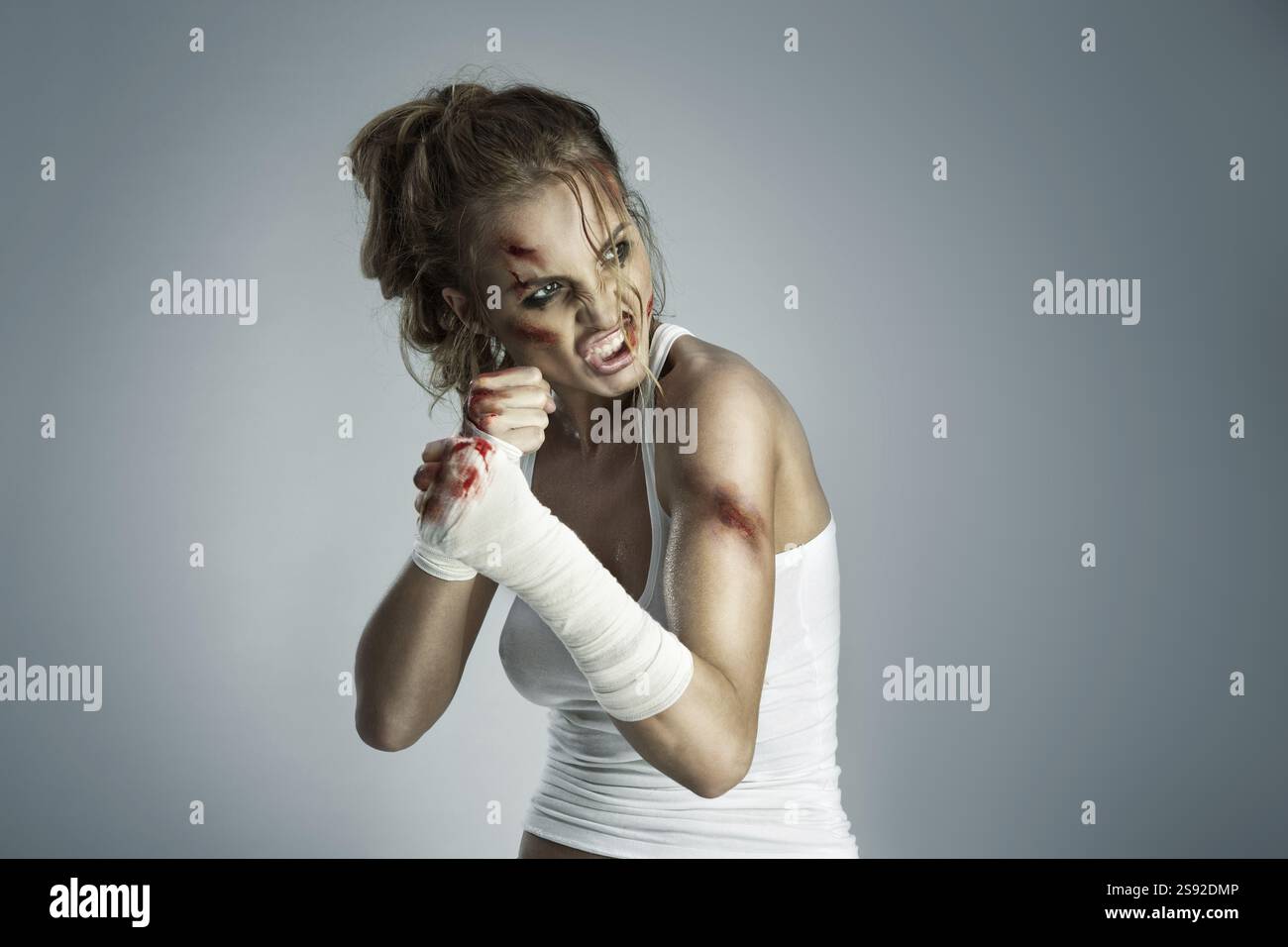 Aggressive female fighter with bruises, wearing a bloody bandage around ...