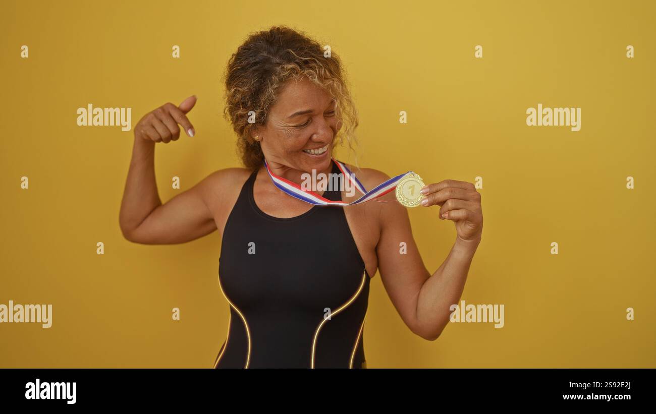 Woman smiling while holding gold medal and flexing muscles against ...