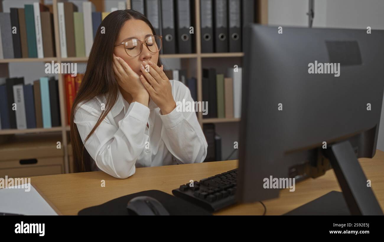 Young woman napping at her desk in an office during work hours ...