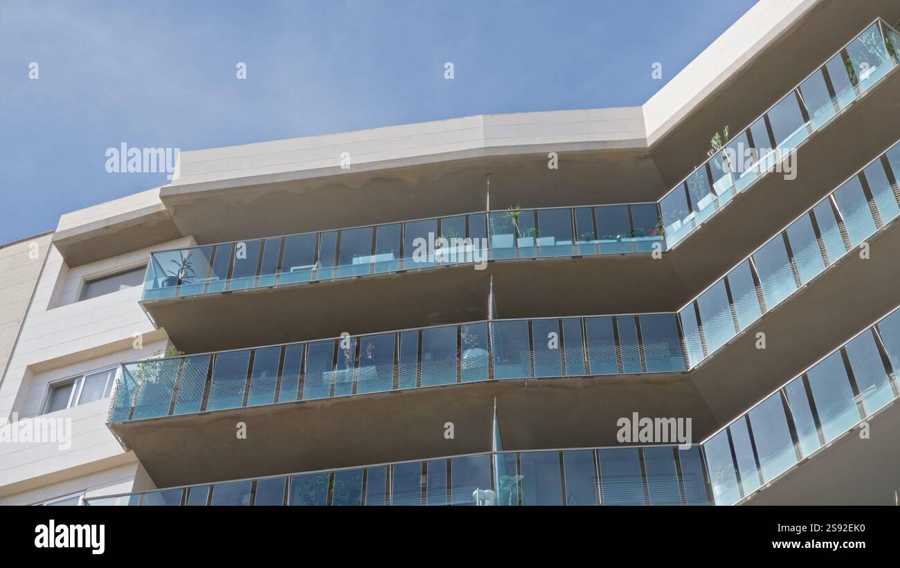 Modern apartment building with glass balconies against a clear blue sky ...