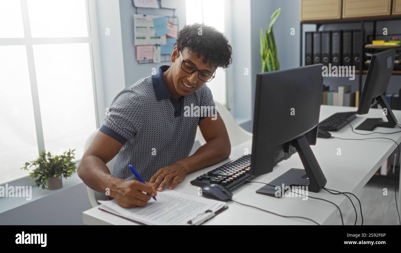 Young man working in a modern office, smiling while filling out ...