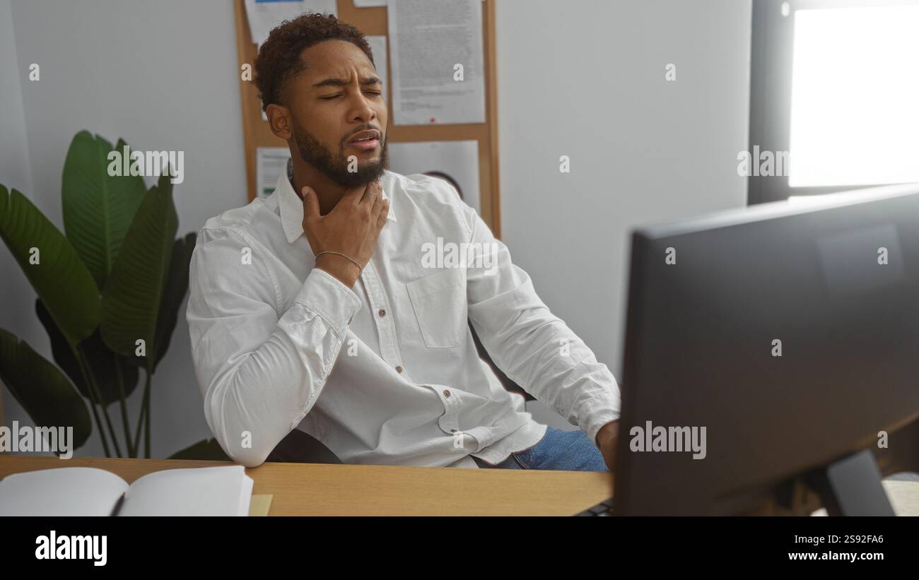 Young man in office rubbing his throat looking uncomfortable while ...