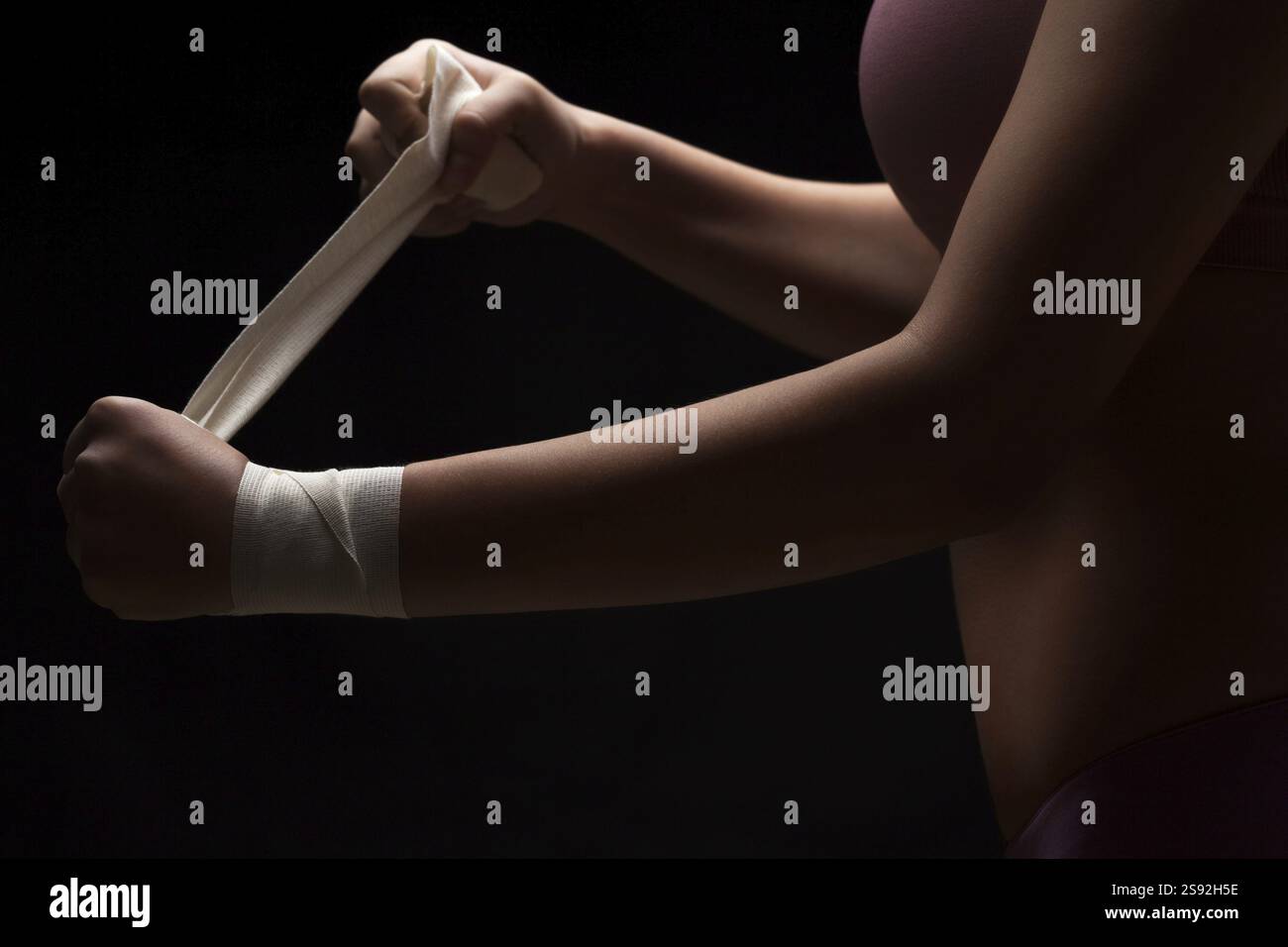 Beautiful and fit fighter preparing for fight or training, wrapping her ...