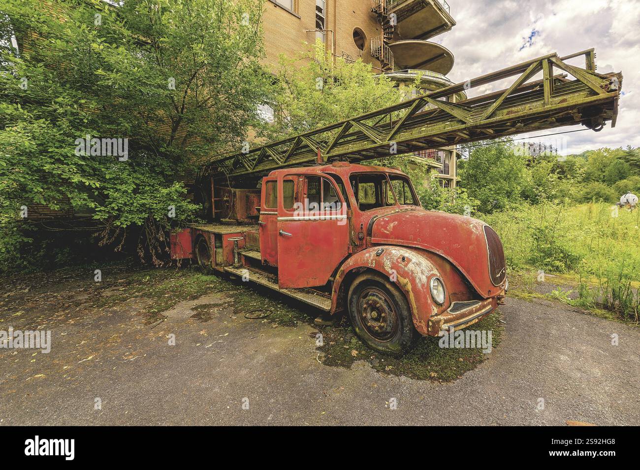 Rusty vehicle with long superstructure next to dense greenery ...