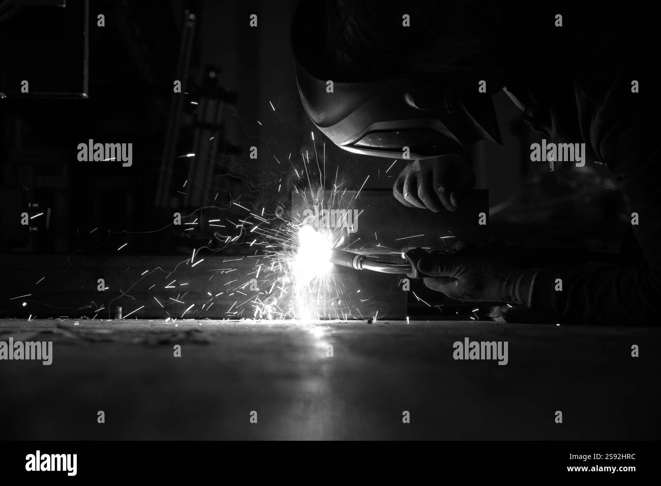 A person wearing a welding mask works on metal with a welding torch ...
