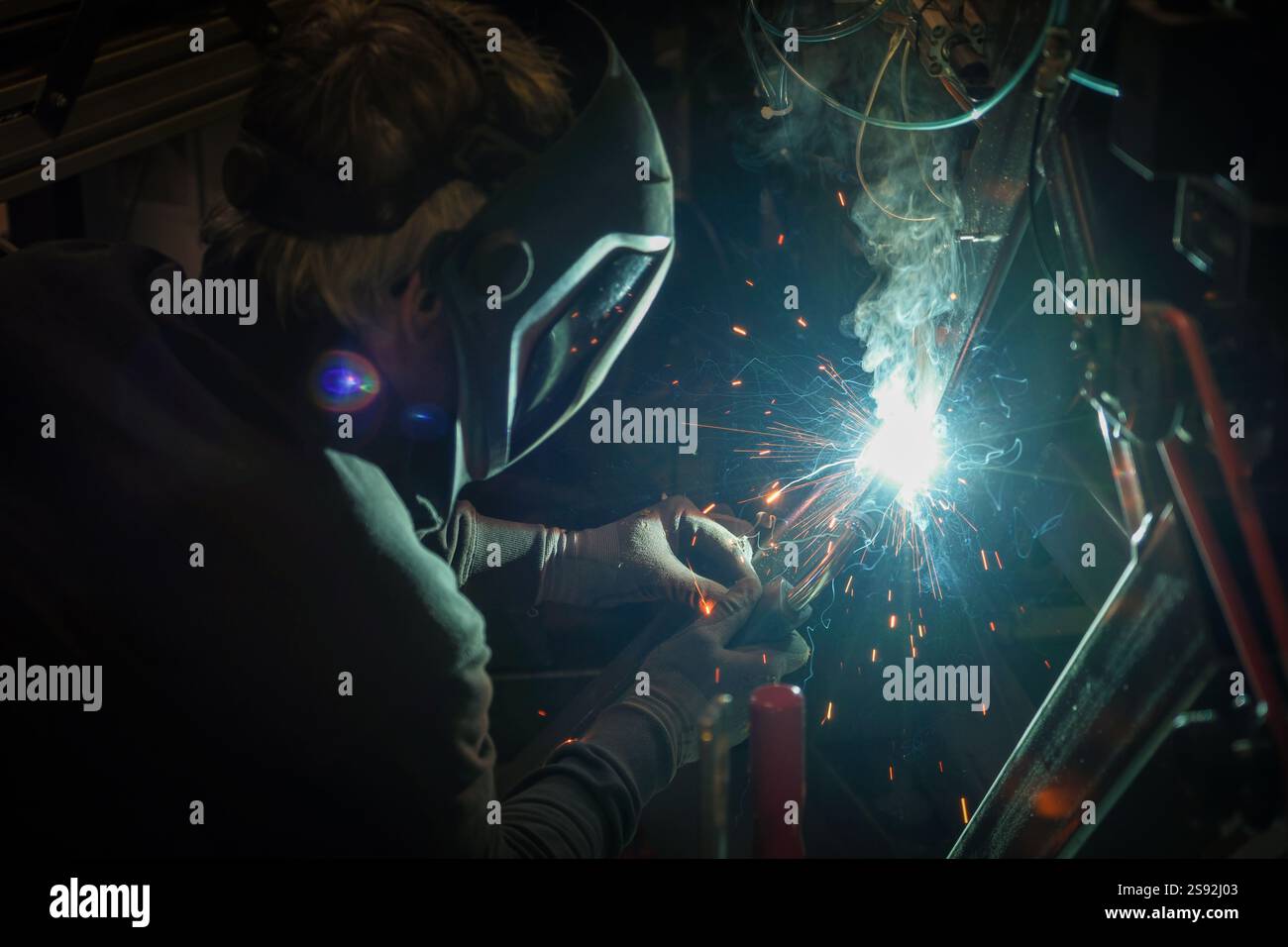A person wearing a welding mask works on metal with a welding torch ...