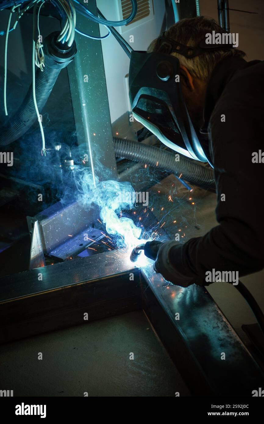 A person wearing a welding mask works on metal with a welding torch ...