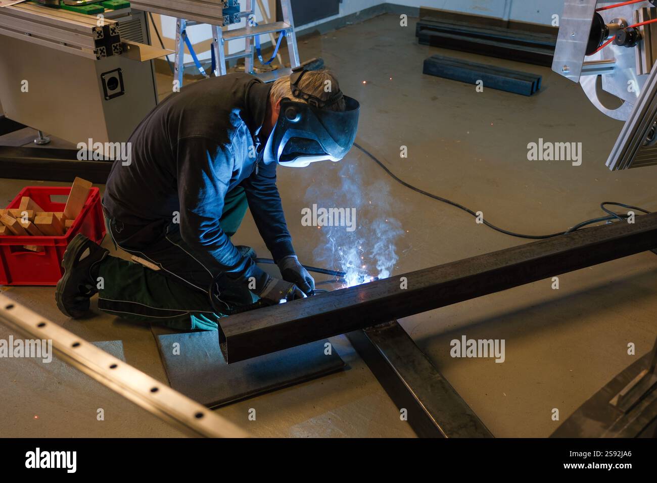 A person wearing a welding mask works on metal with a welding torch ...