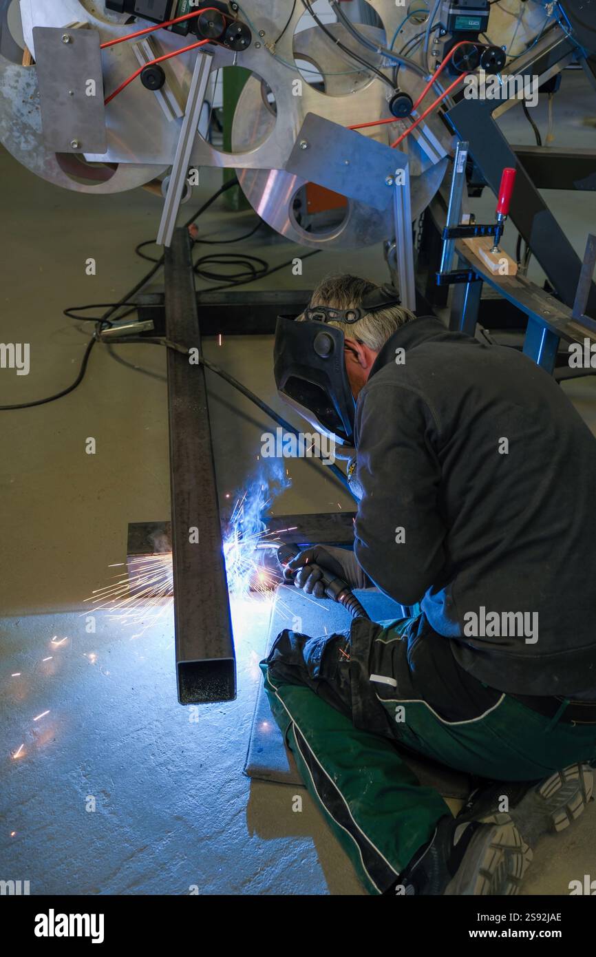 A person wearing a welding mask works on metal with a welding torch ...