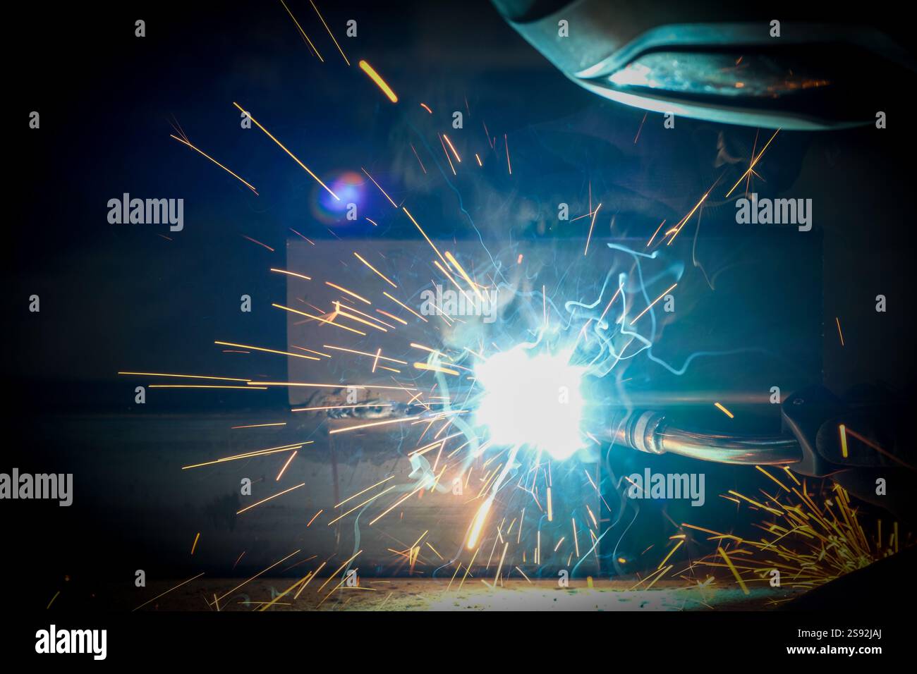 A person wearing a welding mask works on metal with a welding torch ...