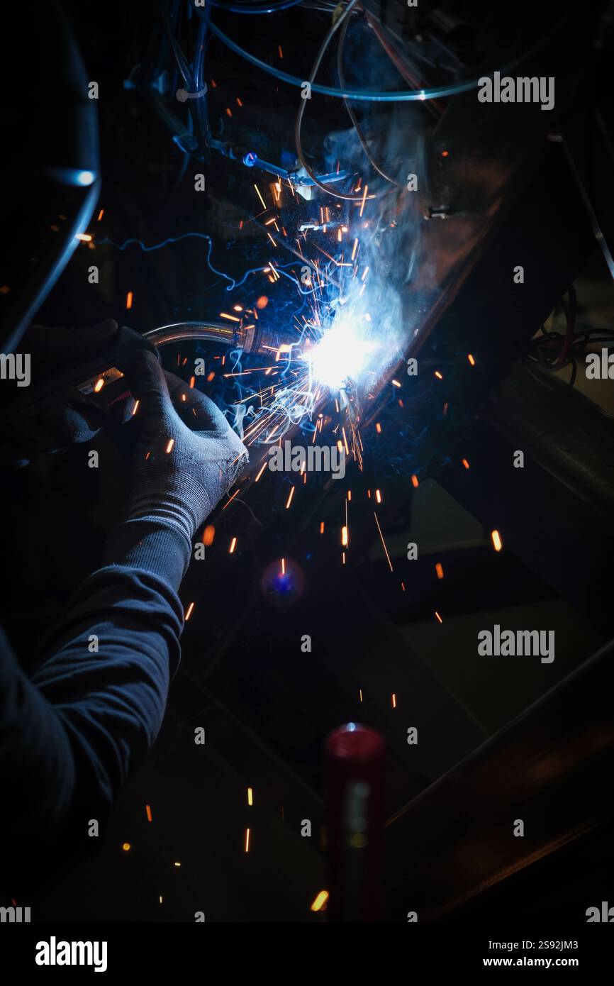 A person wearing a welding mask works on metal with a welding torch ...