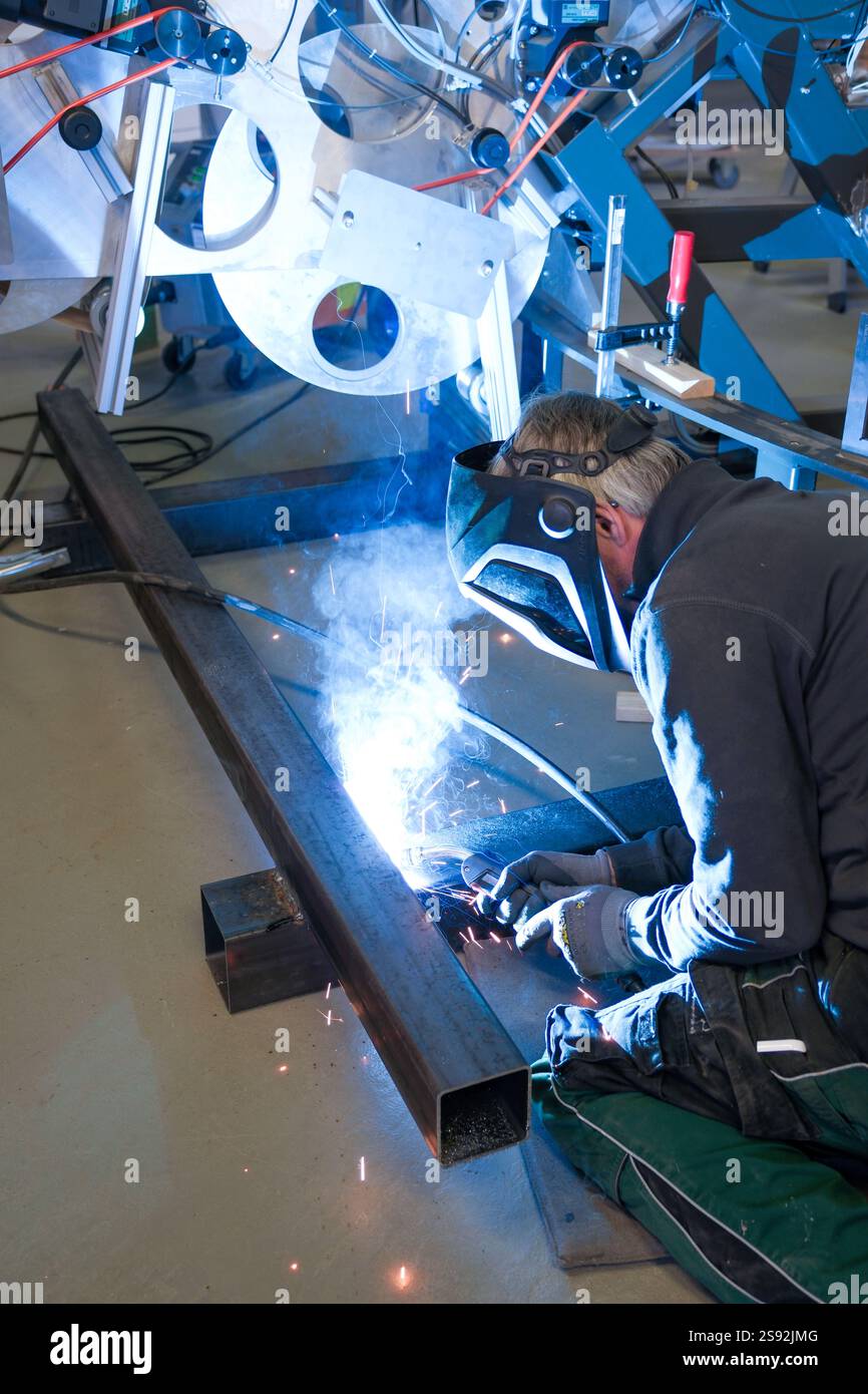 A person wearing a welding mask works on metal with a welding torch ...