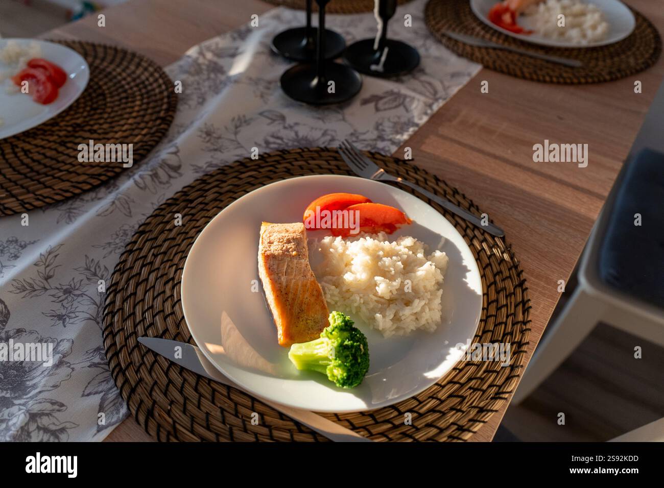 Rice with red fish and vegetables in sunshine on the table. Healthy ...